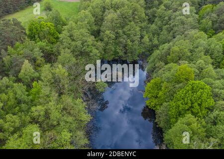 a forest lake nestled in a deciduous forest in spring - aerial view ...