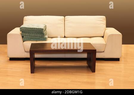 Comfortable white sofa and wooden coffee table with books on yellow ...