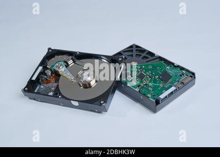 Two defective computer hard drives, head and board at a white ...