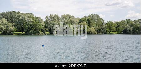green shore of lake in dimissed pit at urban park, shot in bright sunny ...
