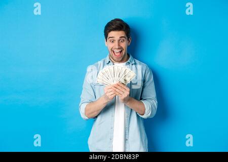 Excited successful man counting money, looking satisfied at cash and ...