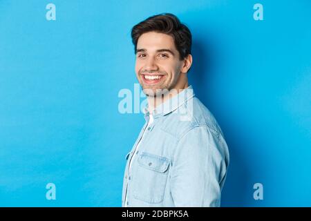 Happy and confident man turn head at camera, winking and smiling ...