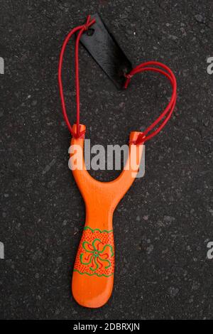 Handmade orange slingshot catapult. Y-shaped wooden stick with elastic ...