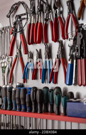 Grey wall with many hanging tools in workshop Stock Photo - Alamy