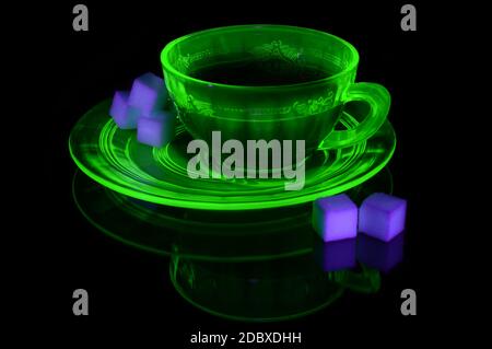 A glowing Uranium Glass Teacup and Saucer under some ultraviolet light ...