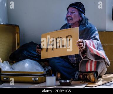 A homeless person holds a sign asking for help during a cold day in ...