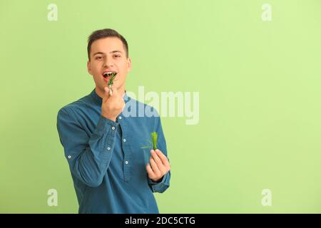 Young man eating wheatgrass on white background Stock Photo - Alamy