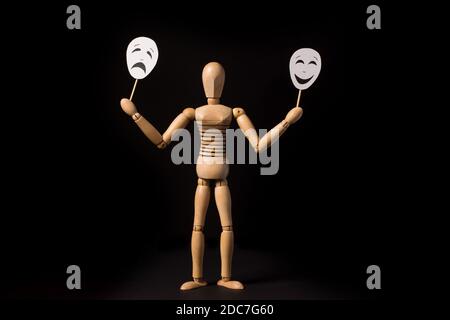 Wooden puppet doll on hinges holds a mask in hands and covers her face ...
