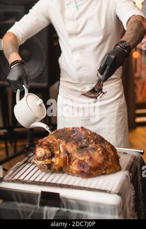 Chef, pouring alcohol into a frying table with meat. Cold ice smoke ...