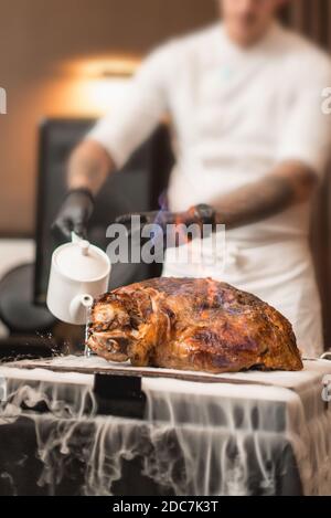 Chef, pouring alcohol into a frying table with meat. Cold ice smoke ...