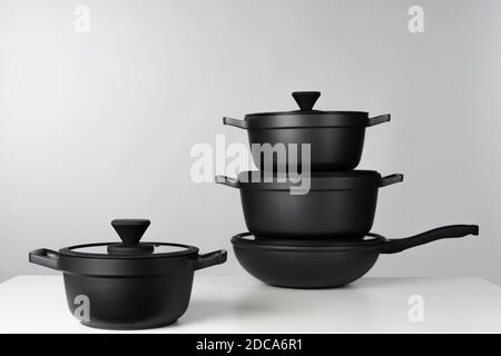 Black cooking pots on grey background front view Stock Photo - Alamy