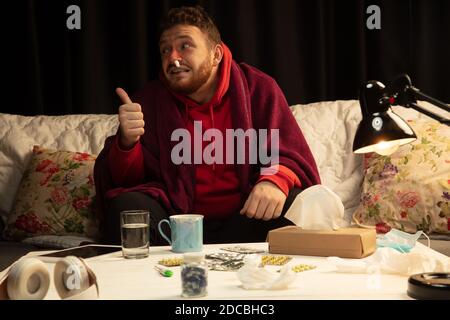 Rainy nose. Young man wrapped in a plaid looks sick, ill, sneezing and ...