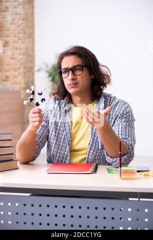 Male student with book and molecular model in library Stock Photo - Alamy