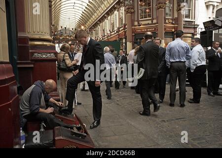 Shoe cleaner is polishing the shoes of a buissnesman in Leadenhall ...