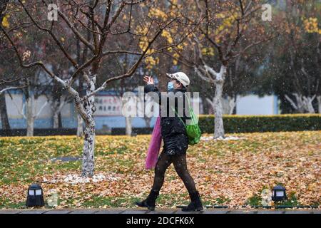 Beijing, China. 21st Nov, 2020. A woman walks on a street in snow in ...