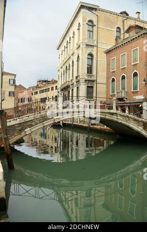 Canal with an arching foot bridge over it in Venice Stock Photo - Alamy