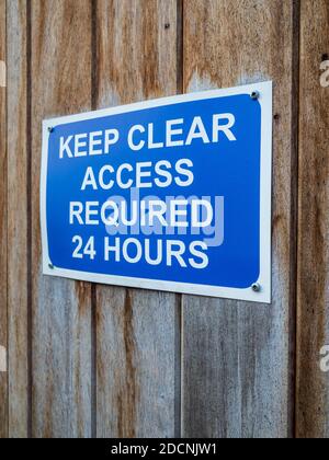 Keep clear 24 access required sign at business entrance roller shutter ...