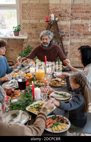 Caucasian three generation family praying during a lunch in the garden ...