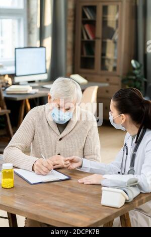 Patient signing paper at desk in aesthetic clinic Stock Photo - Alamy