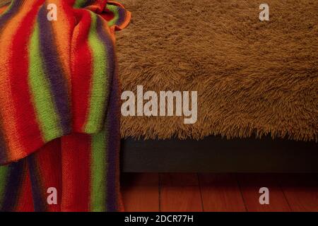 A striped knitted plaid is laid over a brown shaggy fur blanket with ...