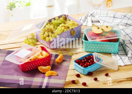 Fruits and vegetables in plastic containers on a wooden background ...