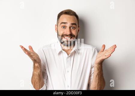 Close-up of awkward manager shrugging and smiling with sorry look ...