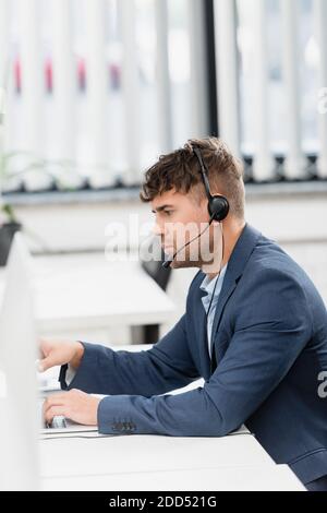 Handsome agent with headset typing on keyboard Stock Photo - Alamy