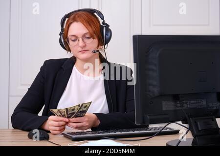 Young woman at home counts dollar money cash with smartphone checks ...