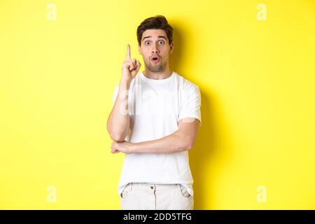 Thoughtful guy suggesting solution, raising finger in eureka sign and ...
