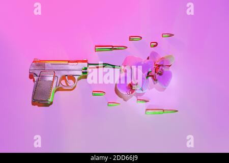 The golden gun shoots an orchid flower, next to fly bullets on a pink ...
