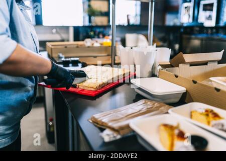 Midsection of female chef preparing take out containers at counter in ...
