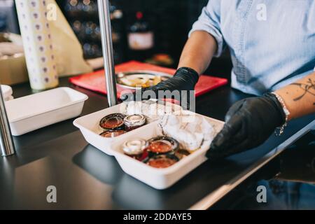 Midsection of female chef preparing take out containers at counter in ...