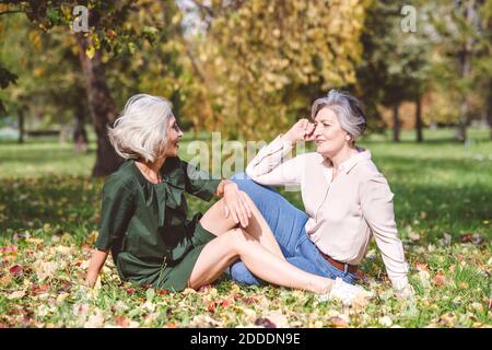 Beautiful mature women sitting on bench against grey background Stock ...