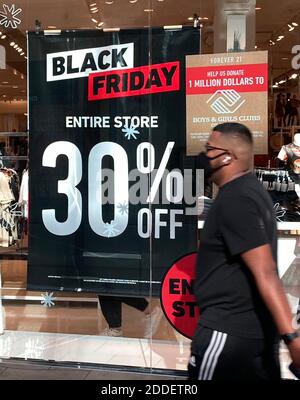 A Black Friday shopper wearing a face mask carries bags at the Glendale ...