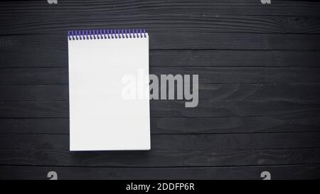 Blank paper notebook on brown wooden table background. Top view with ...