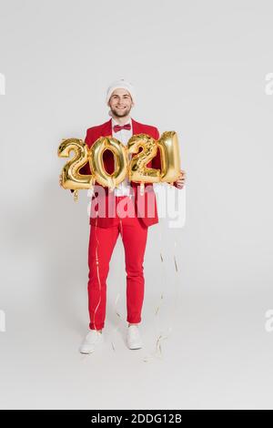 Smiling man in santa hat having video conference using laptop at home ...