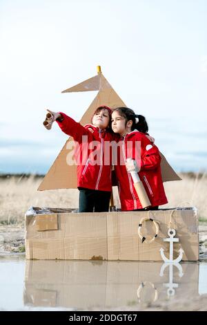 Side view of cheerful kids with handmade spyglass standing in handmade ...