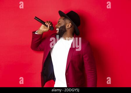Passionate black male singer performing against red background, singing ...