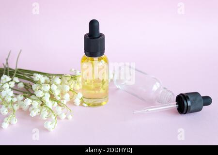 Bottle with essential oil and lily-of-the-valley flowers on color ...