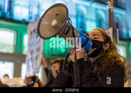 A woman wearing a face mask chants slogans on a megaphone during a ...
