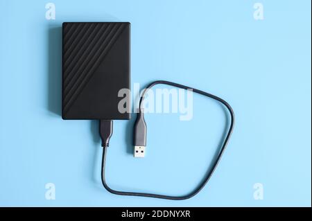 external hard drive black color with connection cable on blue ...