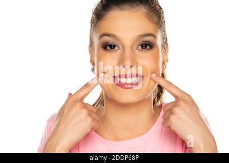 Young woman forcing her smile with her fingers on white background ...
