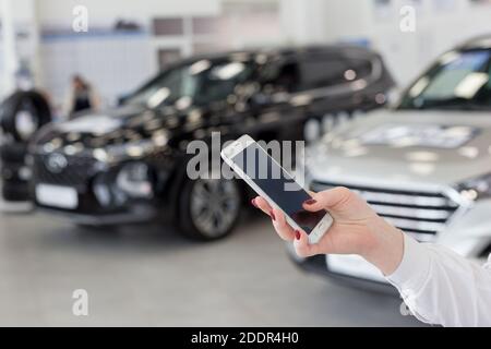 Woman dealer using mobile smart phone at dealer showroom. Modern ...