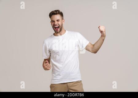 Delighted handsome guy screaming and showing winner gesture isolated ...