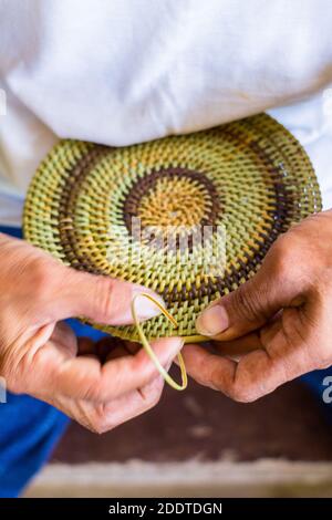 A pinikas artisan working on a basket using local materials at the ...