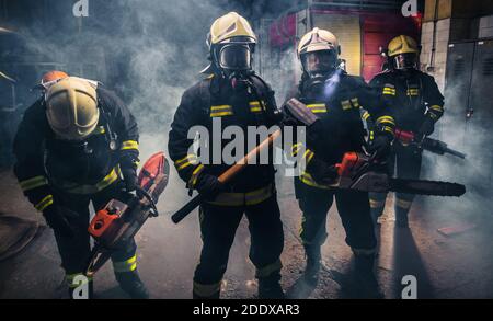 Group of firefighters with chainsaw and sledge hammer practicing in the ...