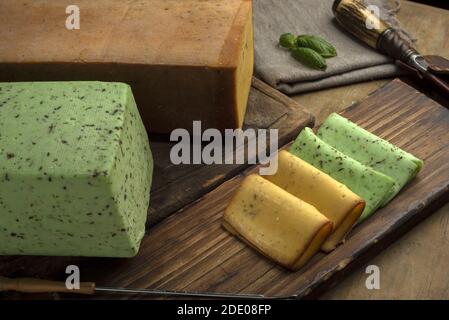 Block of yellow cheese with slices on wooden board with cherry tomatoes ...