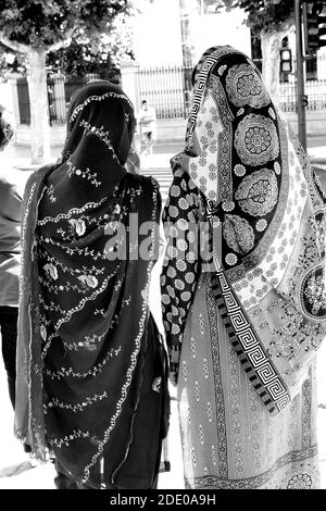 A grayscale of Indian women in traditional costumes filling buckets ...