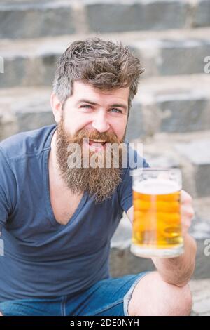 Hipster with long beard looks relaxed. Bearded hipster holds beer mug ...