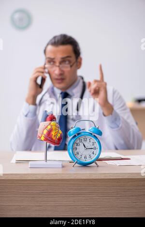 Male doctor cardiologist in time management concept Stock Photo - Alamy